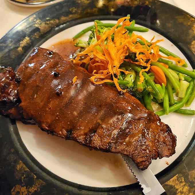 A glazed New York Strip with crispy carrot strings and fresh vegetables, looking like it means business.