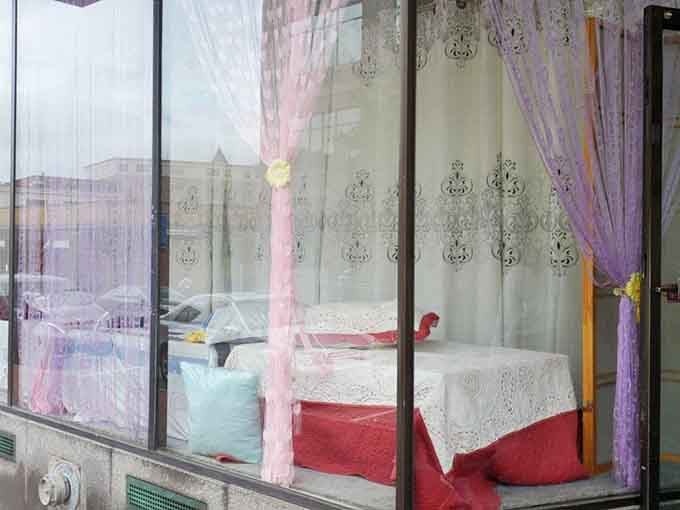Soft curtains, lace tablecloths, and pastel pillows fill this dreamy window display, proof that elegance lives at bargain prices.