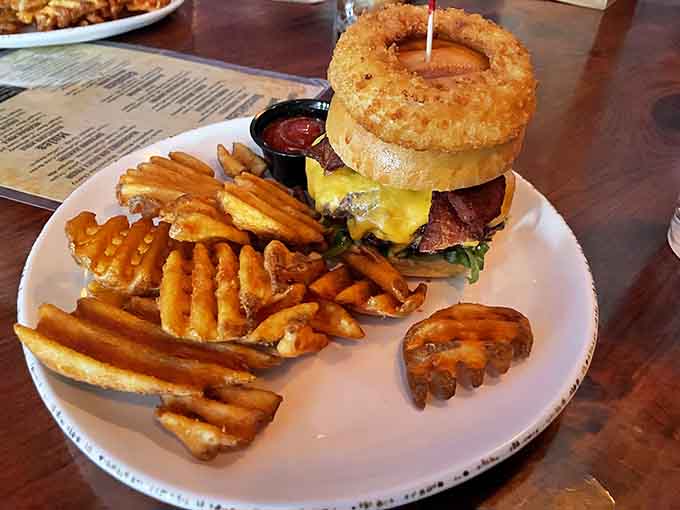 Behold the Wild West burger crowned with an onion ring, served alongside waffle fries that deserve their own fan club.