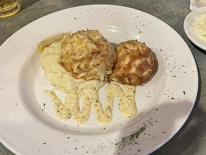 Two golden broiled crab cakes sitting on mashed potatoes. This is what dreams look like on a plate.