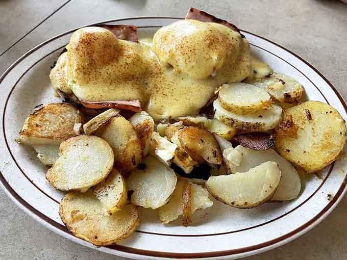Eggs Benedict so golden and glossy, even the potatoes beside them look proud to be there.