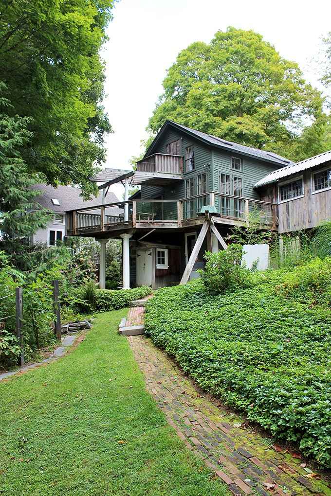 A brick path, lush greenery, and a cabin that looks like it grew straight out of the hillside.