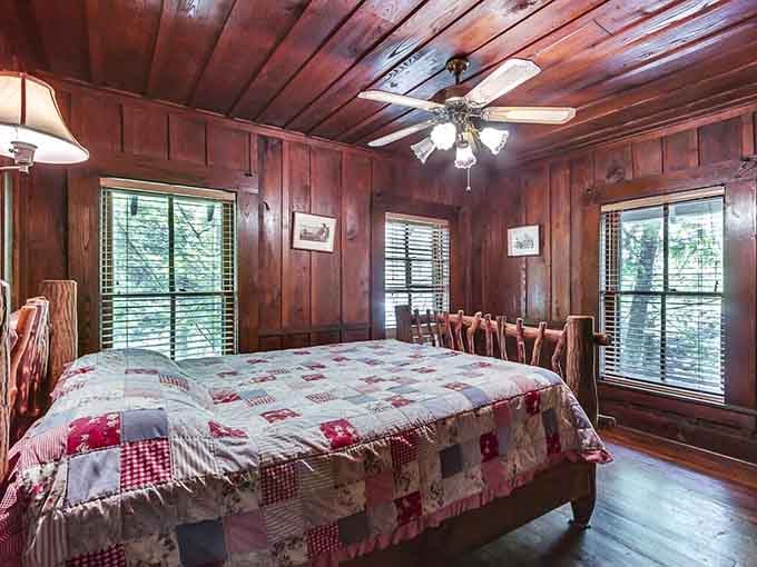 Rich wood walls, a patchwork quilt, and windows full of trees. This bedroom says "sleep well" and means it.