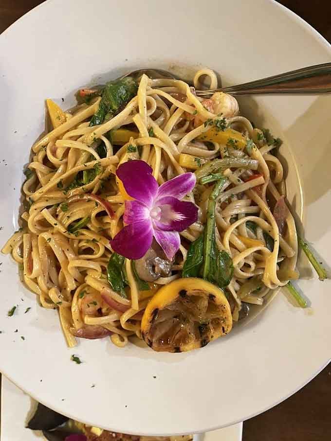 Rasta pasta topped with a fresh orchid, because some dishes insist on arriving dressed for the occasion.