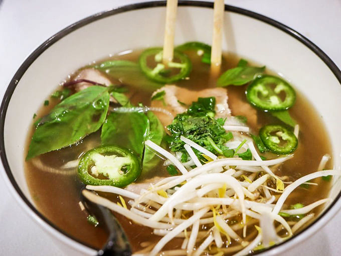 This bowl of beef pho arrives steaming hot, loaded with fresh jalapeños and bean sprouts for customizing.