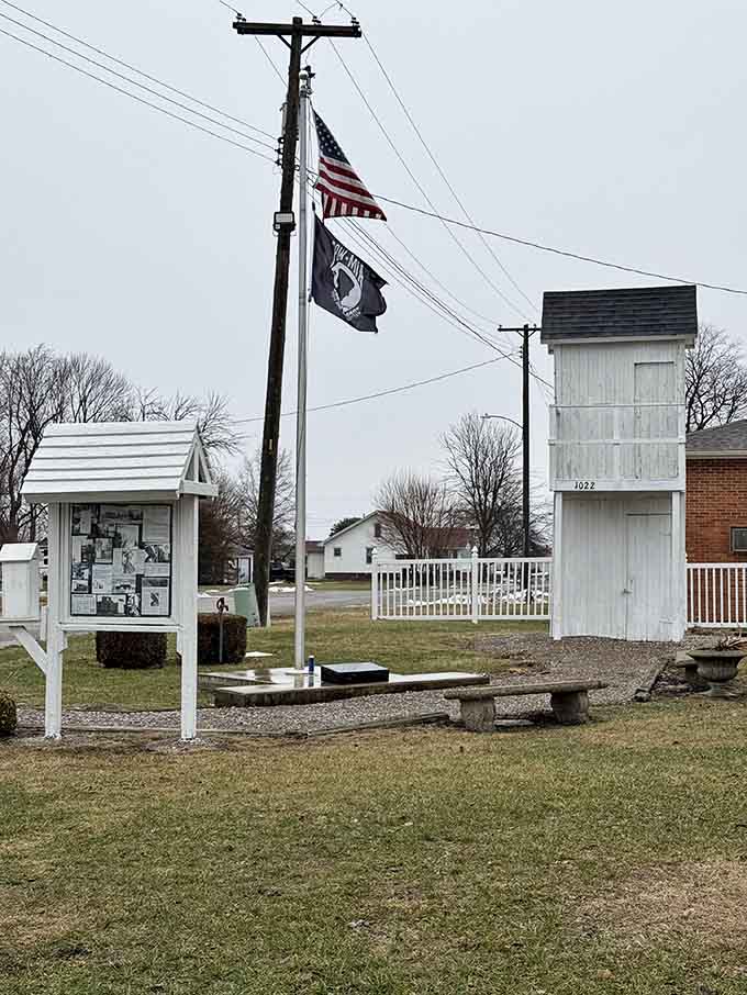 An American flag, a POW-MIA flag, a park bench, and a two-story outhouse. Small towns contain multitudes.