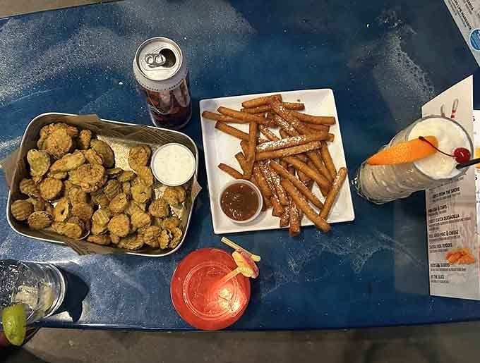 Fried pickles, churro fries, and a festive drink on a blue table, this is what a good afternoon looks like.