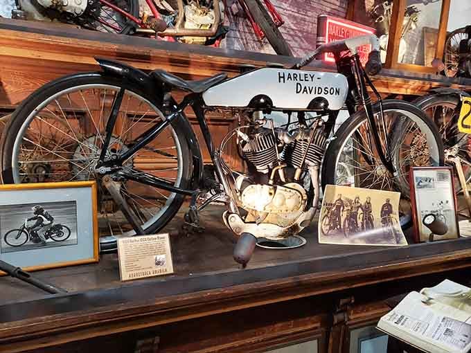 This bare-knuckle Harley-Davidson board track racer, surrounded by vintage photographs, is pure mechanical poetry from a fearless era.