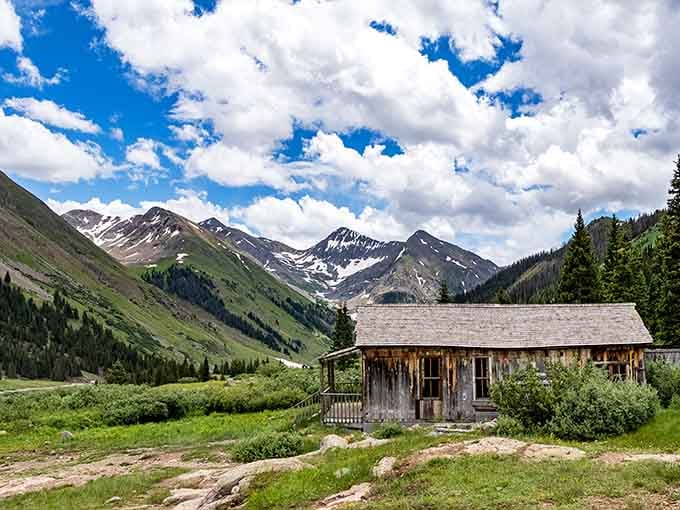 A weathered cabin at Animas Forks sits small and humble against snow-capped peaks that make everything else feel wonderfully insignificant.