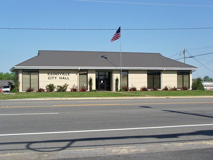 Rainsville City Hall sits neat and confident along the road, with the American flag snapping crisply overhead like it owns the place.