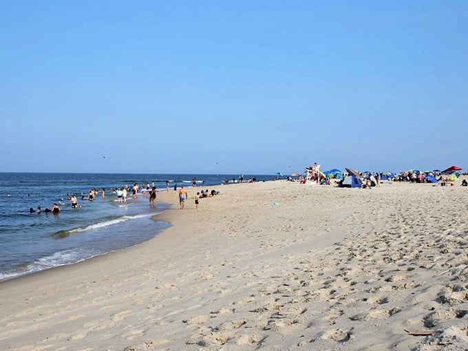 Gentle bay waves lap at sandy Hook's southern shore, offering tranquil swimming with perfect blue skies.