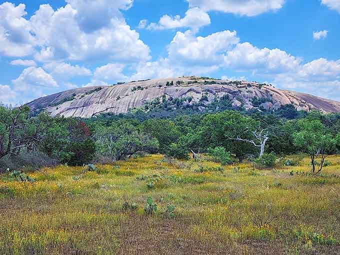 Enchanted Rock commands the horizon under puffy clouds, looking exactly like the kind of place legends are born from.