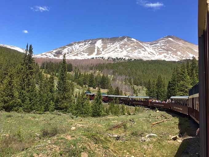 Snow-capped peaks rising above the treeline while a full train curves through alpine meadows &mdash; Leadville doesn't do subtle scenery.