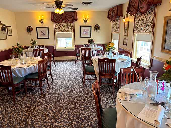 White tablecloths, bird prints, and soft wall sconces — Robin's Nest dining room feels like Sunday dinner at your most elegant aunt's house.