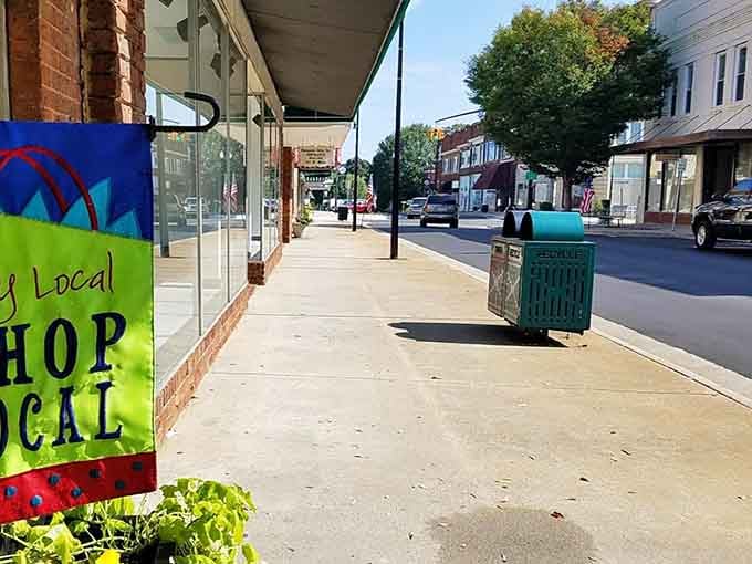 A "Shop Local" flag fluttering on a sunny Roxboro sidewalk is basically the town's entire philosophy in two words.