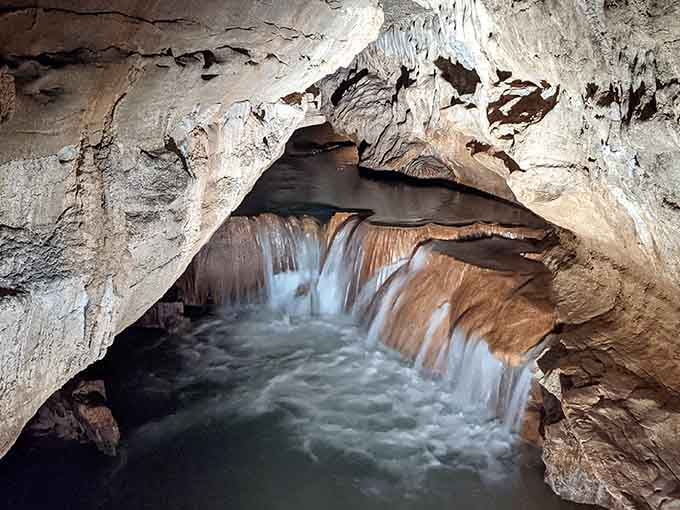 Underground streams flowing over sculpted rock create an otherworldly scene that cameras barely capture.