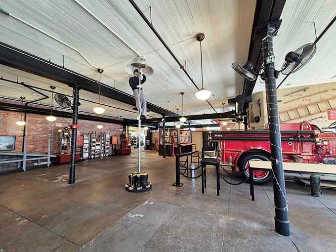 Original brass fire poles still standing tall, with a mannequin mid-slide to remind you this place was the real deal.