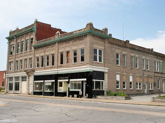 This weathered Webb City corner building wears its age like a badge of honor, its ornate brickwork and faded green trim whispering tales of busier days gone by.