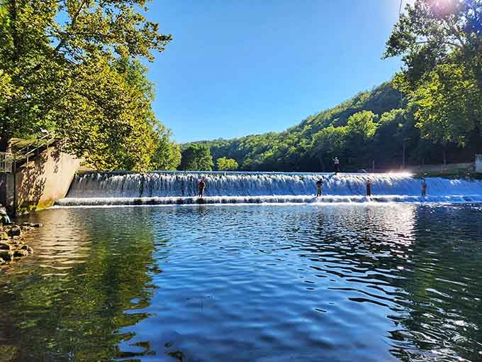 Anglers standing atop that cascading dam look like they've wandered into a painting nobody wanted to sell.