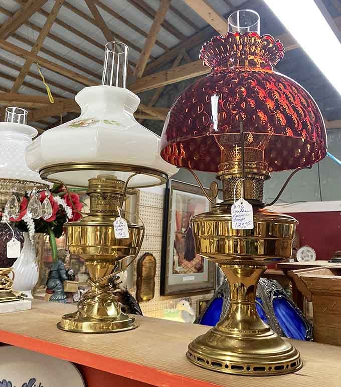 Two brass Aladdin-style lamps side by side, one with a painted milk glass shade, one crowned in rich ruby glass, both absolutely glowing with character.
