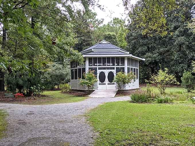 A white gazebo tucked among the trees, looking like it wandered out of a Southern fairy tale.