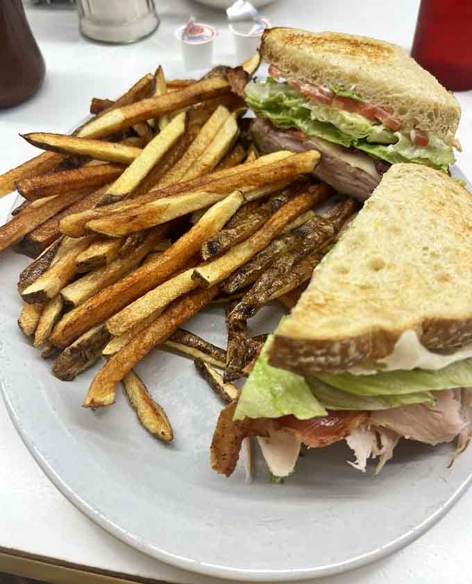 Perfectly golden fries, a towering turkey club stacked with fresh lettuce and tomato, proof that lunch deserves equal respect here.