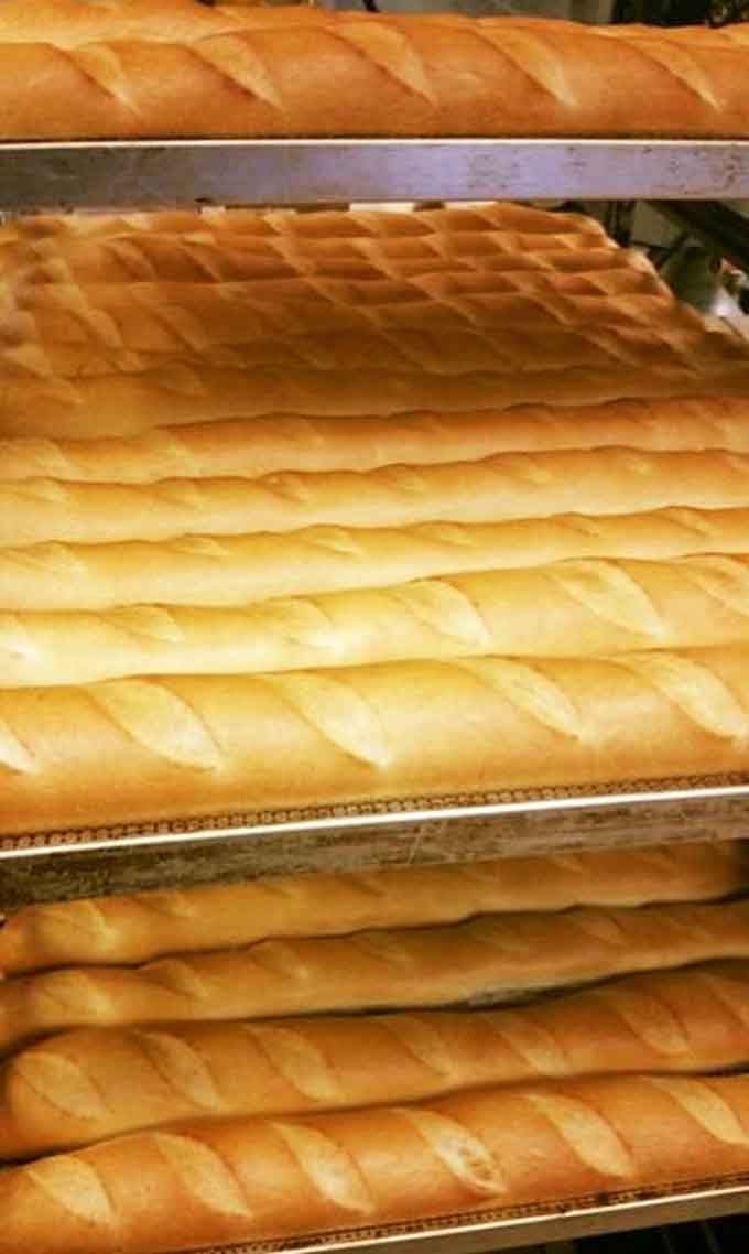 Fresh loaves stacked like edible gold bars, each one destined to disappear faster than common sense at buffets.