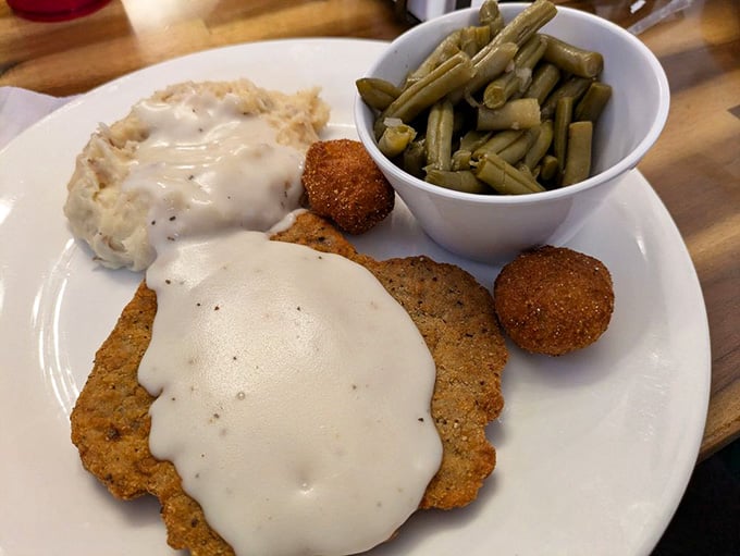 Country fried steak smothered in white gravy, with green beans and hush puppies on the side. Southern cooking at its most sincere.
