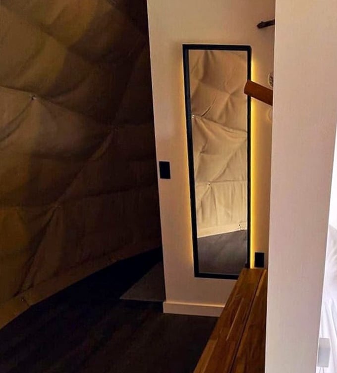 A full-length mirror with warm backlit glow, because even in the wilderness, you deserve to look good.