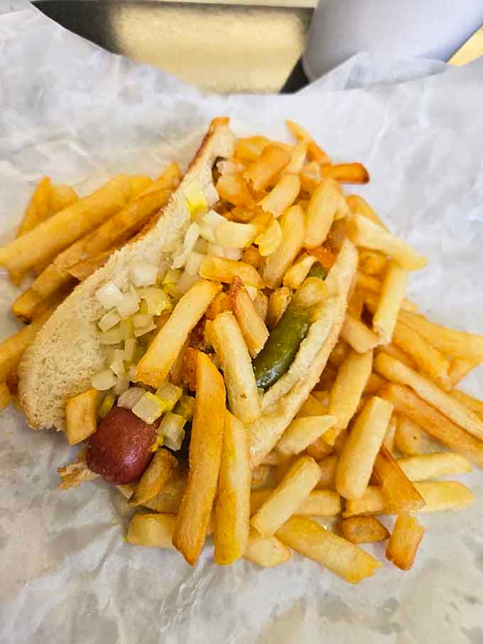 Chopped onions, tangy pickles, and a mountain of crispy fries piled high, this hot dog means serious, glorious business.