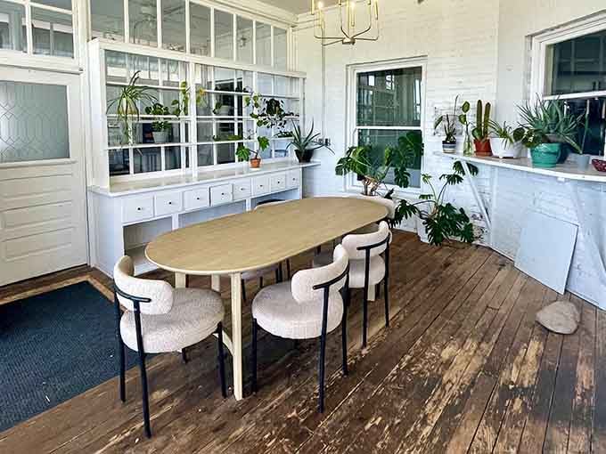 Sunlight, houseplants, and worn wooden floors. This dining space feels like a deep breath you didn't know you needed.