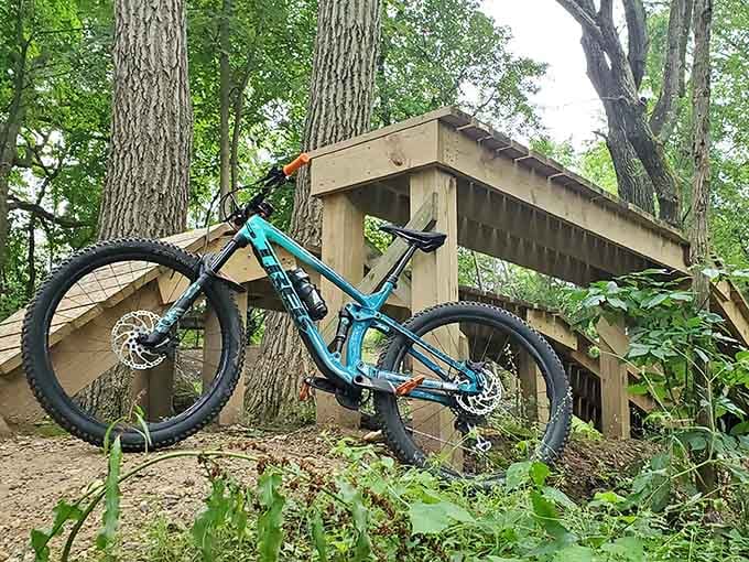 A well-loved mountain bike rests beside a wooden feature, ready for its next round of glory.