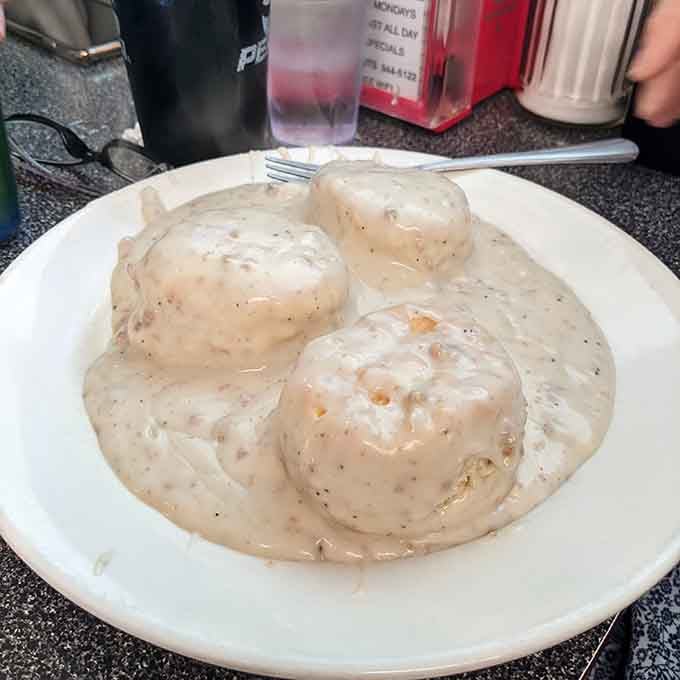 Biscuits and gravy done right. Three fluffy biscuits completely buried under a thick, peppery blanket of goodness.