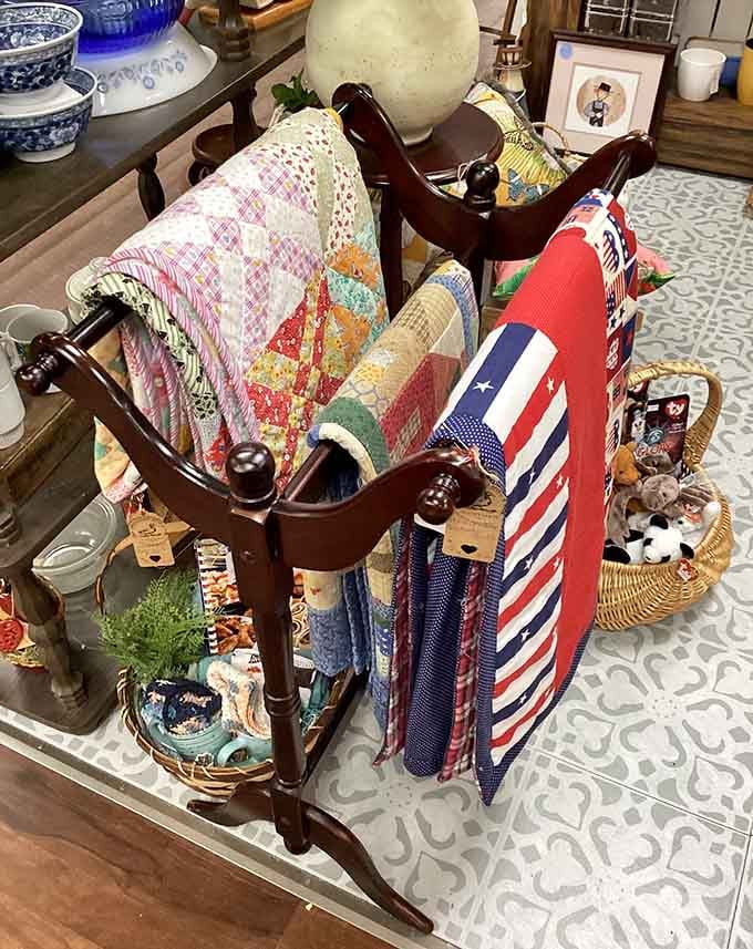 Handmade quilts draped over a wooden rack, each one a patchwork story worth taking home.
