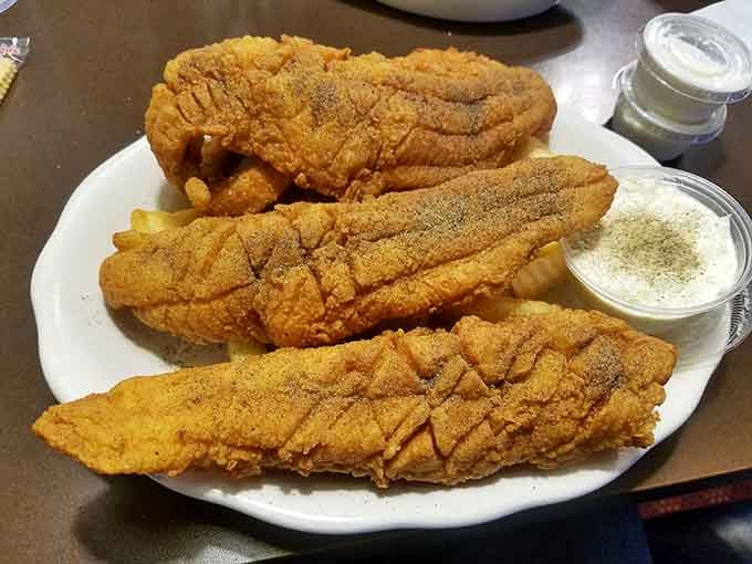 Three golden catfish fillets with a side of tartar sauce. Simple, confident, and absolutely impossible to argue with.
