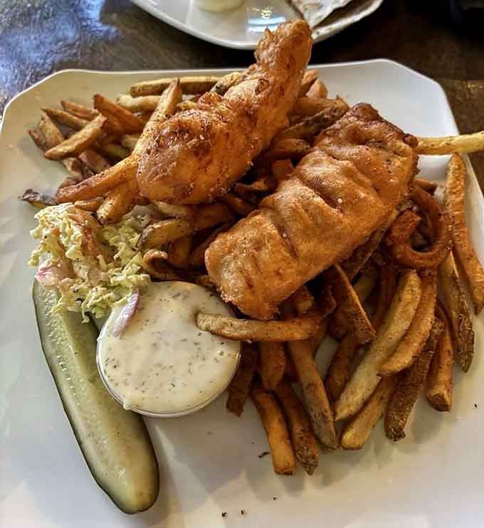 Two beer-battered cod filets sitting on a mountain of house cut fries, looking absolutely proud of themselves.