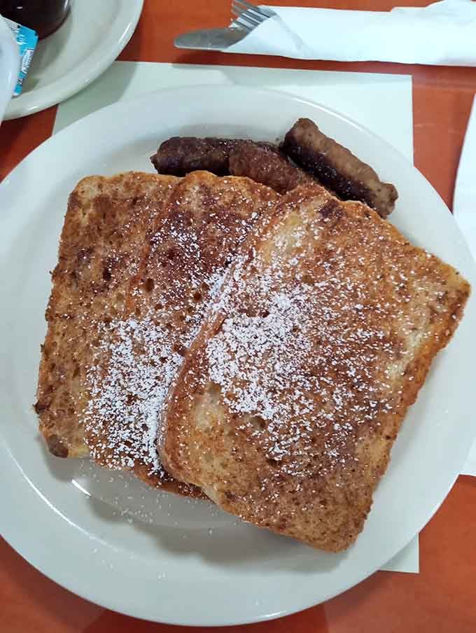 French toast dusted with powdered sugar, flanked by sausage links. Simple, golden, and completely impossible to ignore.