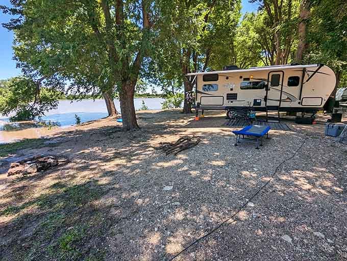 A travel trailer parked under shady cottonwoods at Wolf Creek Park, with the water glittering nearby, is the definition of a perfect slow afternoon.