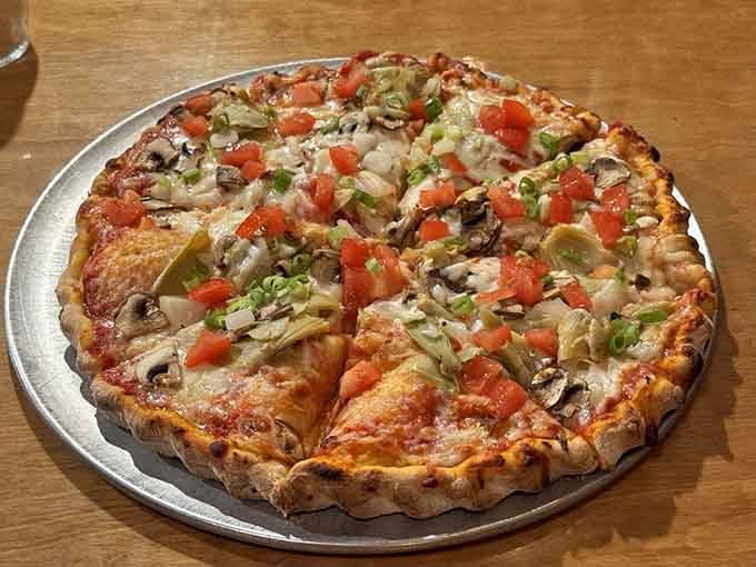 The Veggie pizza arrives loaded with mushrooms, artichoke, tomato, and green onion, looking almost too good to eat. Almost.