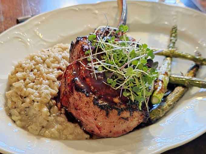 A pork chop over mushroom risotto so beautifully plated, even your phone deserves a moment to appreciate it.