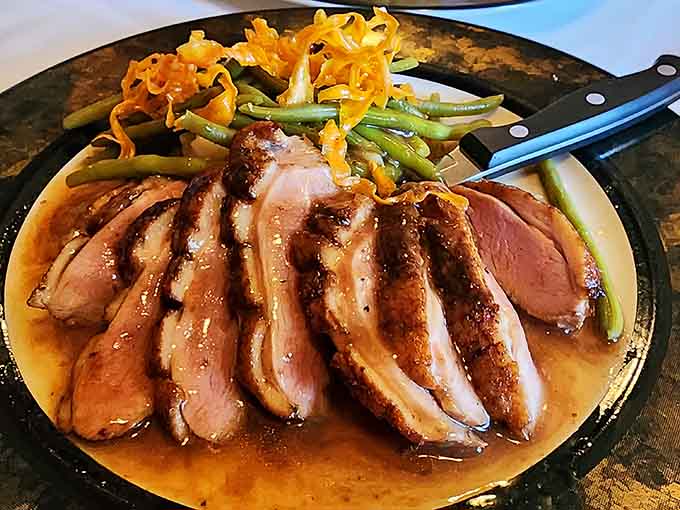 Sliced duck breast fanned out in a rich sauce, the kind of plate that makes you put your phone down.