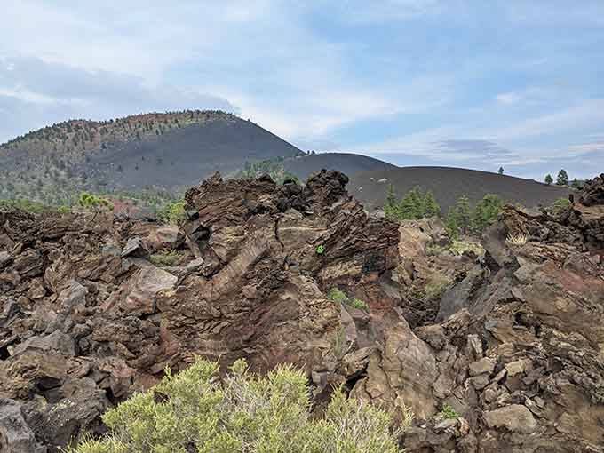 Jagged rust-colored lava rocks in the foreground, a dark volcanic cone behind. Earth's roughest neighborhood, beautifully preserved.