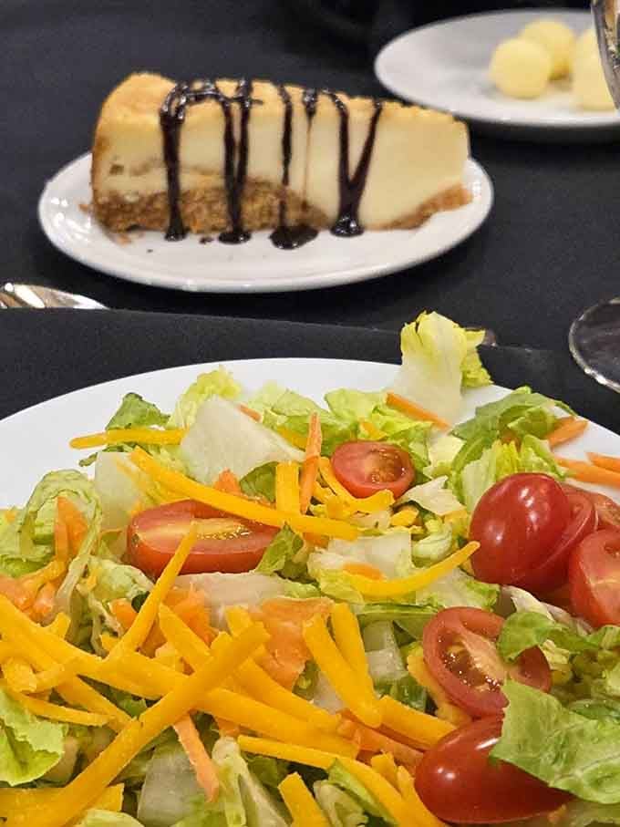 A fresh garden salad up front and a chocolate-drizzled cheesecake waiting patiently in the background. Priorities sorted.