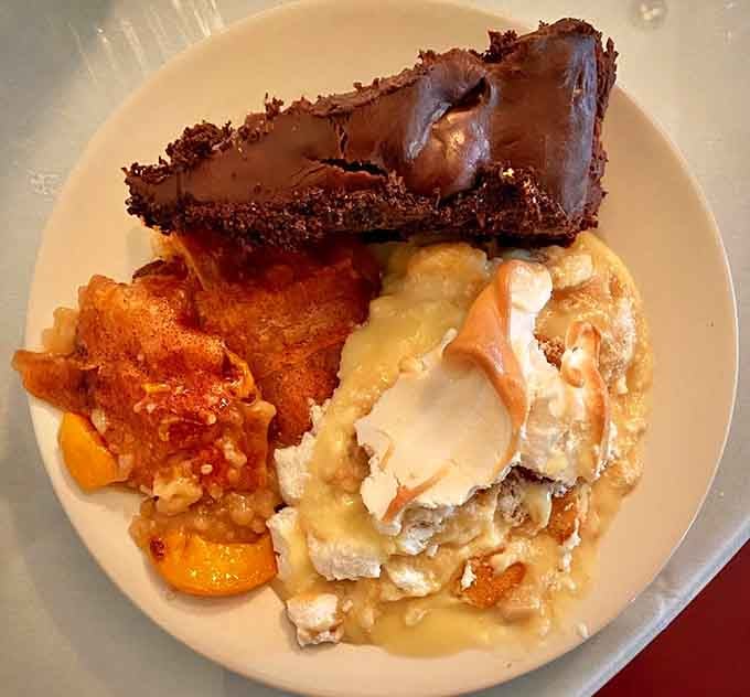 Chocolate cake, peach cobbler, and banana pudding sharing one plate, dessert here isn't a suggestion, it's a full commitment.