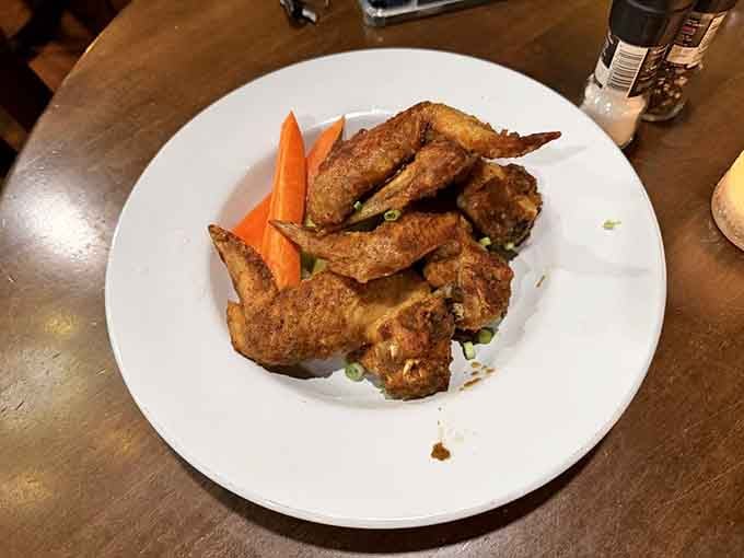 Jerk chicken wings with carrot sticks on the side, proof that paradise has excellent snacking standards.