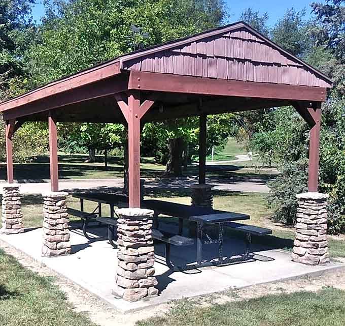 A shaded picnic shelter with stone pillars, the kind of spot that makes you want to pack a lunch and stay all afternoon.