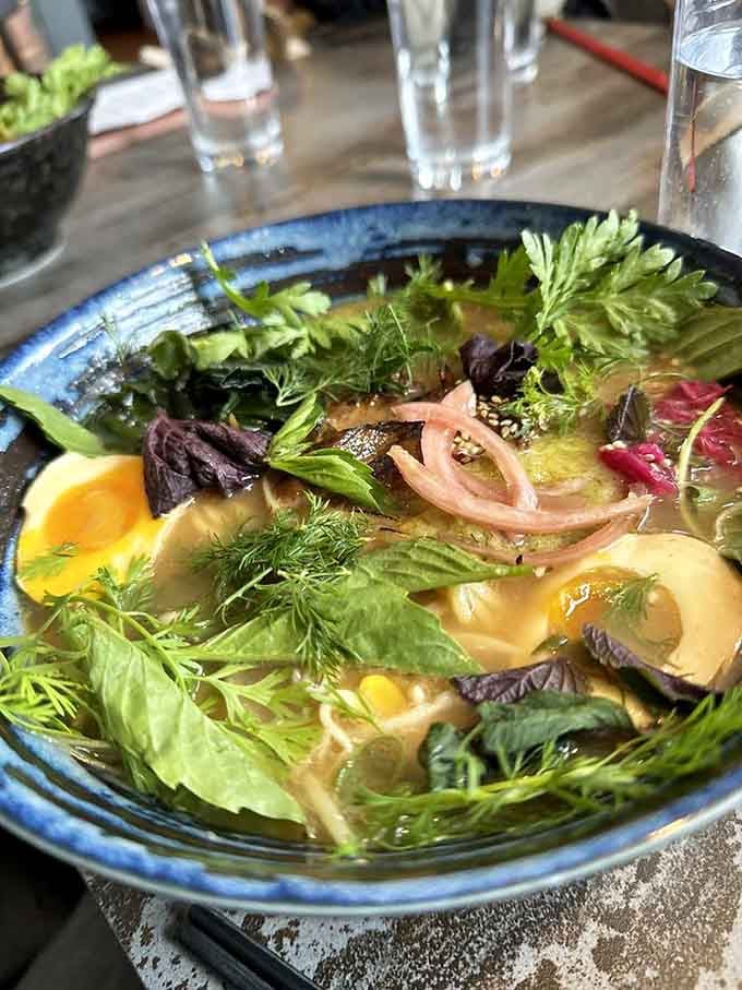 Fresh herbs, pickled shallots, and a golden egg floating in broth so beautiful you'll feel guilty eating it. Almost.