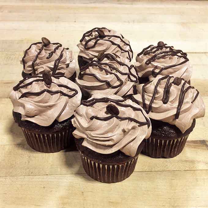 Chocolate cupcakes topped with swirled mocha frosting and a chocolate drizzle. Your willpower never stood a chance here.