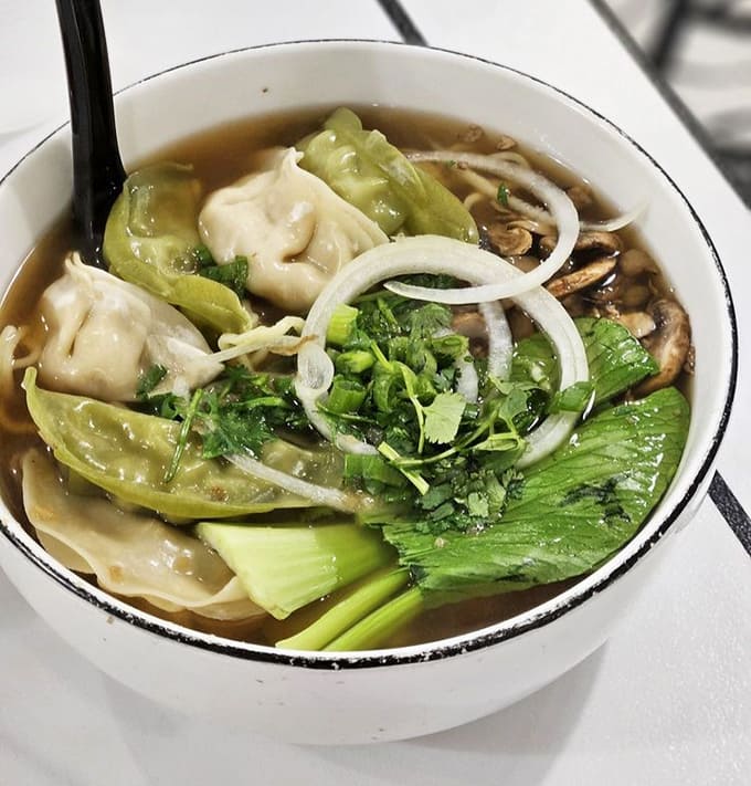 Shanghai dumplings float in savory broth alongside ramen noodles, creating the ultimate comfort bowl experience.