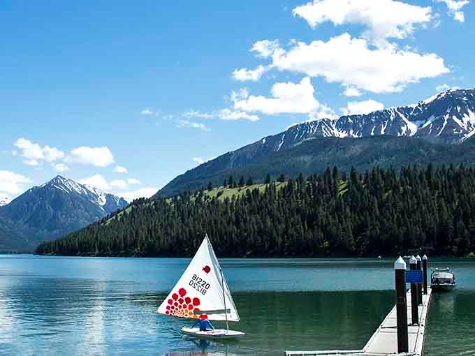 That little sailboat is living its best life, probably humming "Come Sail Away" while gliding across glass.